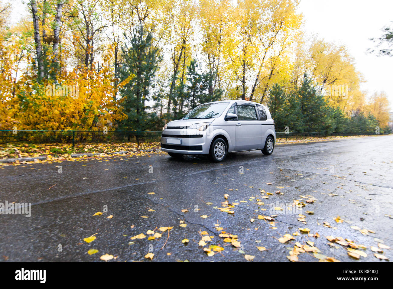 Silver hatchback moving on autumn road Stock Photo - Alamy