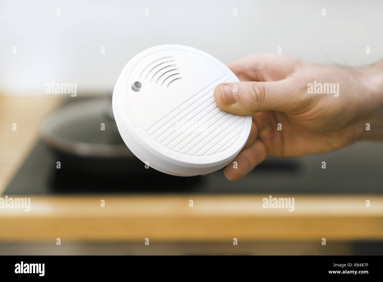 Man holding smoke detector in the kitchen Stock Photo - Alamy