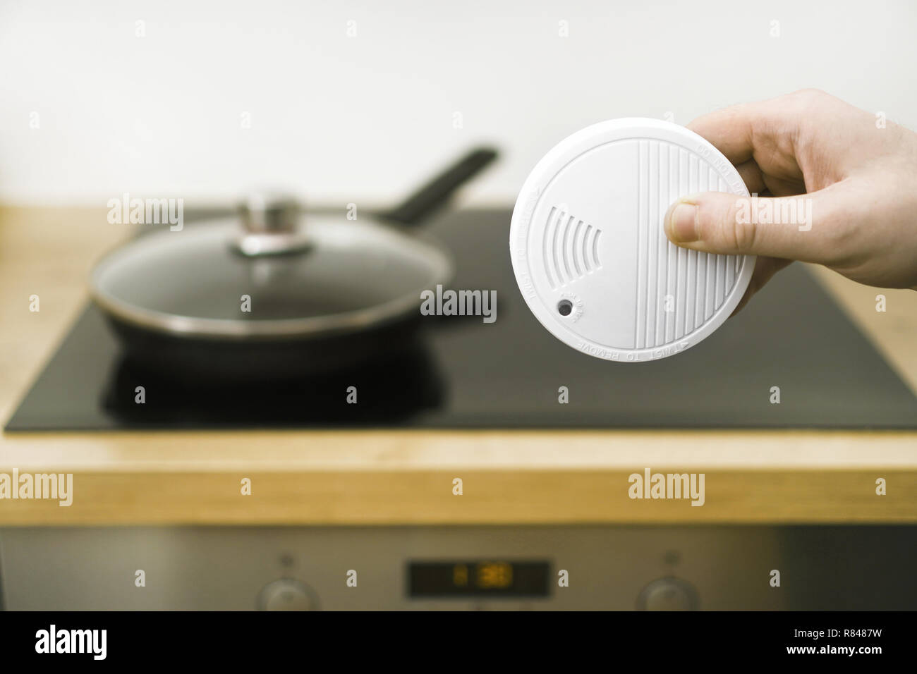 Man holding smoke detector in the kitchen Stock Photo - Alamy