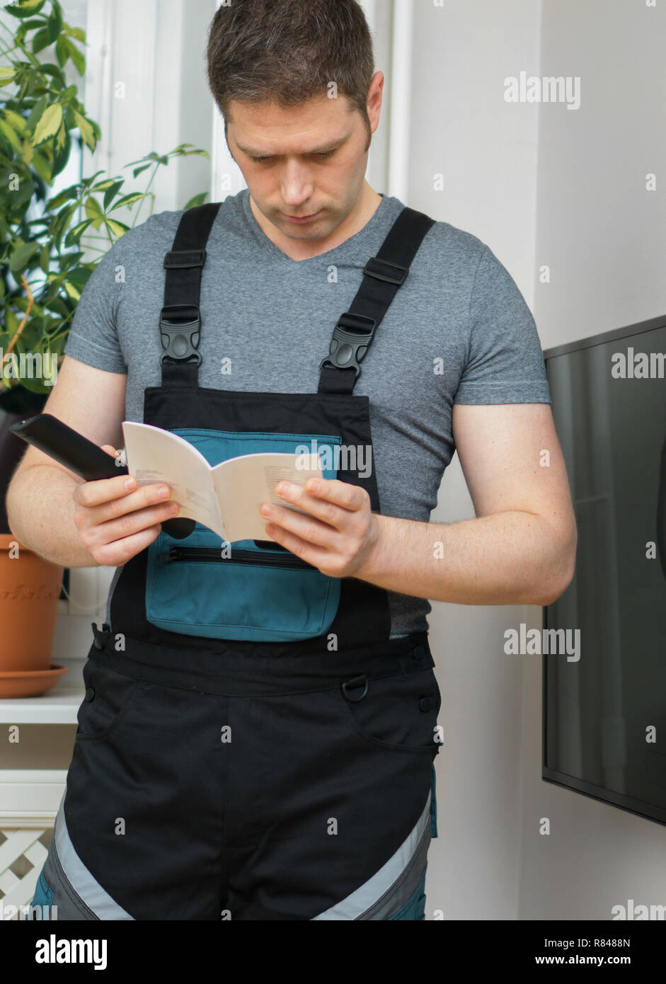 Male technician setting up new TV with instruction Stock Photo - Alamy