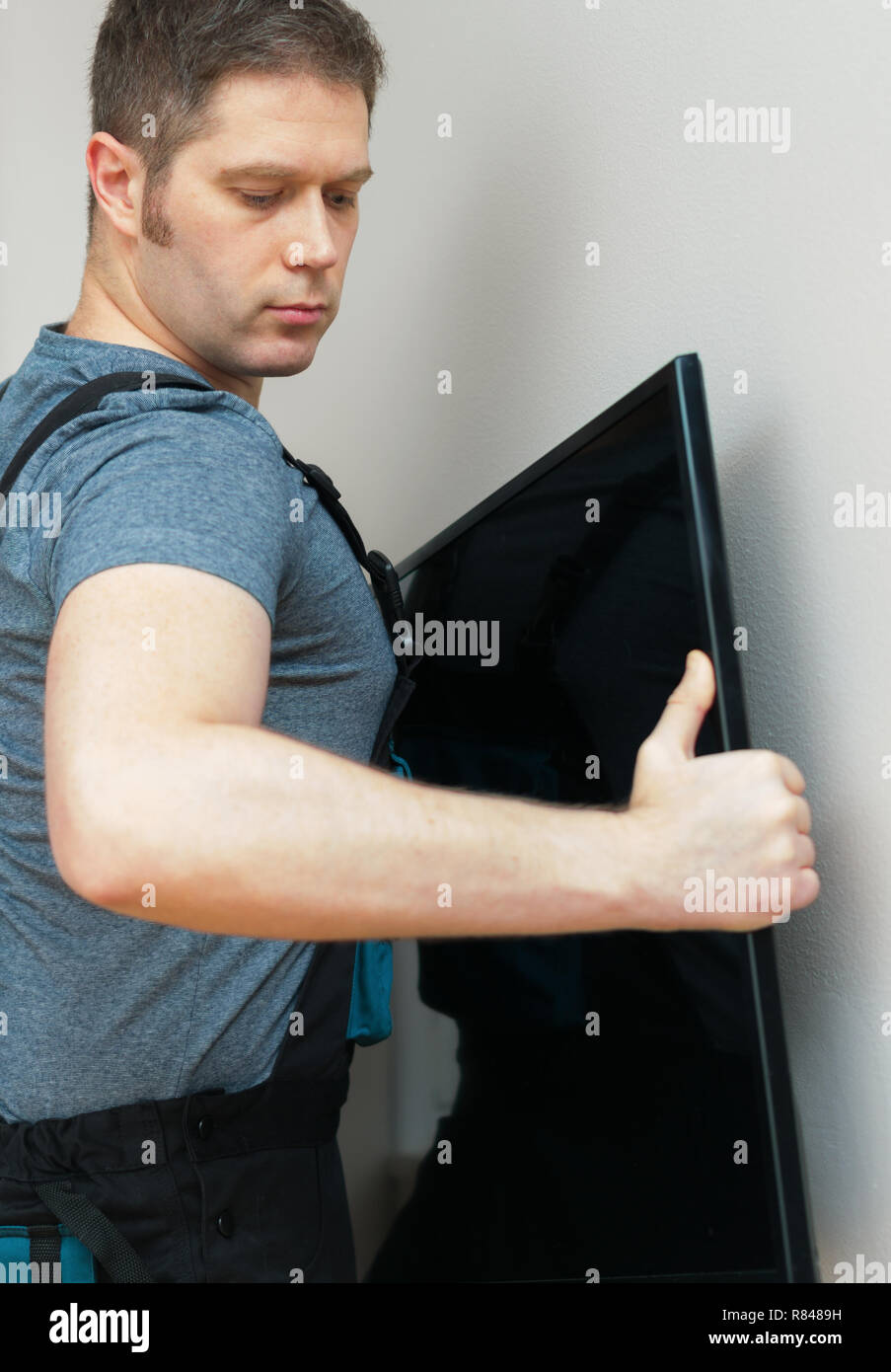 Man mounting new TV on the wall Stock Photo - Alamy