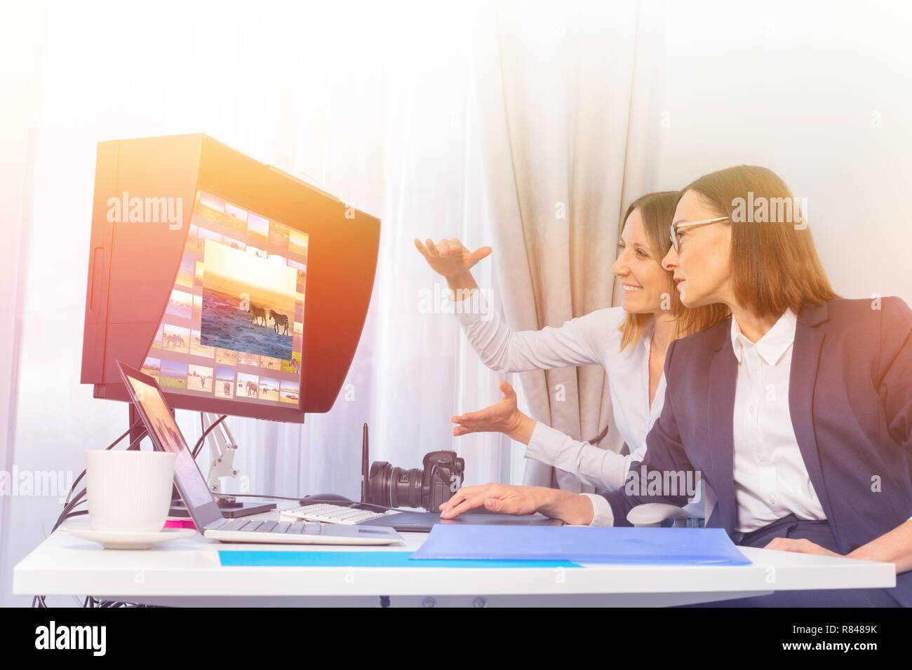 Portrait of female photographer and client working with computer, using ...