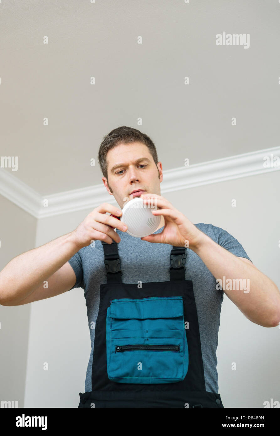 Man checking battery in smoke detector. House maintenance Stock Photo ...