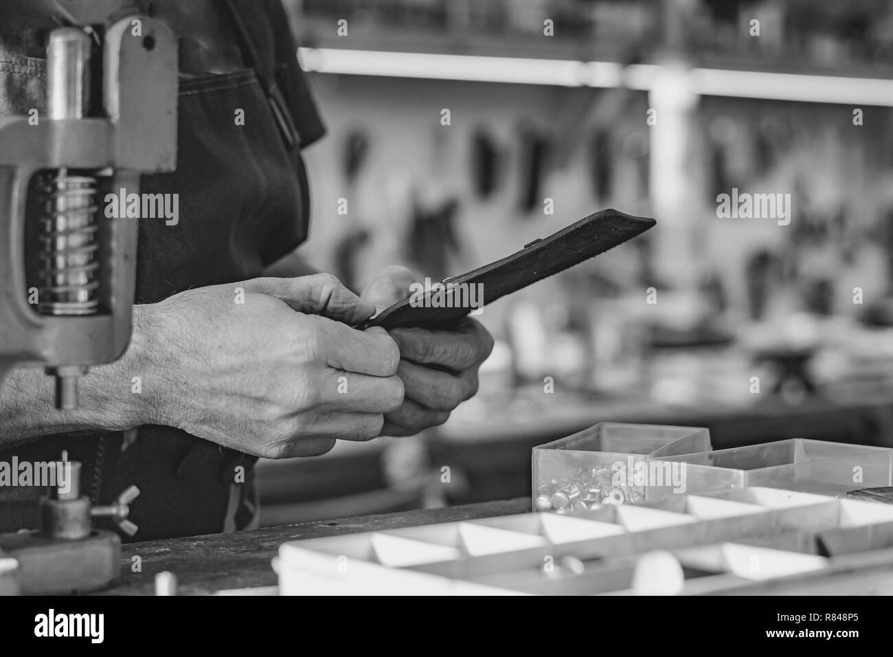 Man works in carpentry workshop. He fixes wooden handle in vice ...