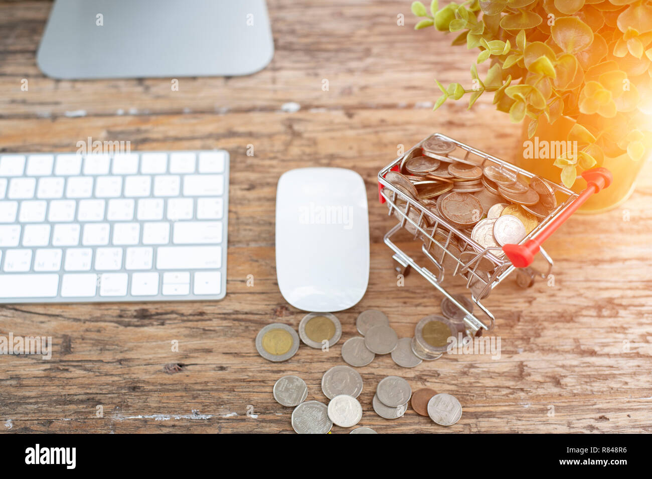 Money and coins to mini shopping cart trolley on table wood background ...