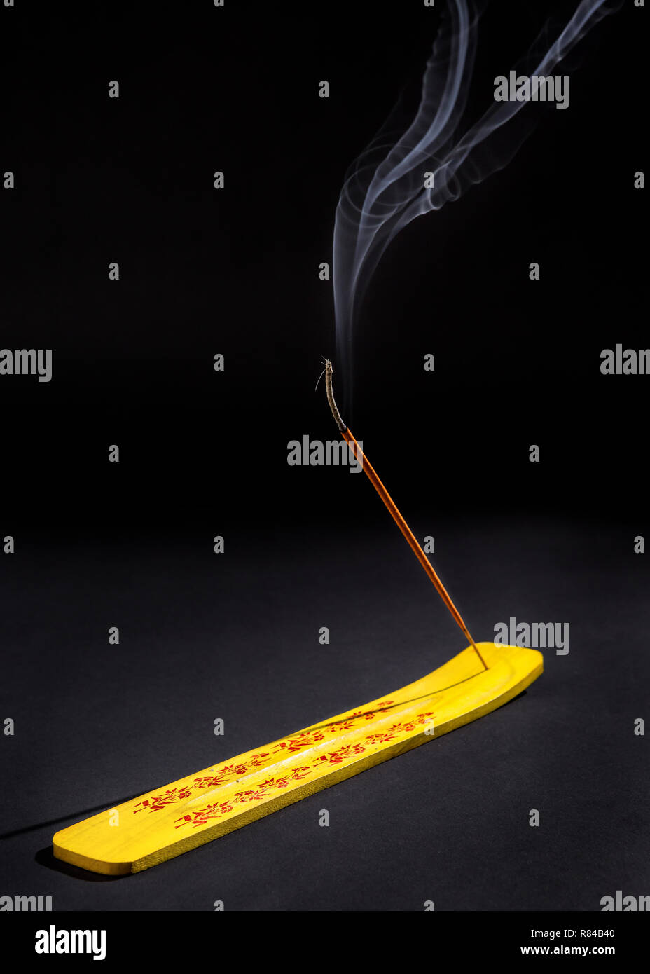Burning incense stick in yellow holder on the dark background with ...