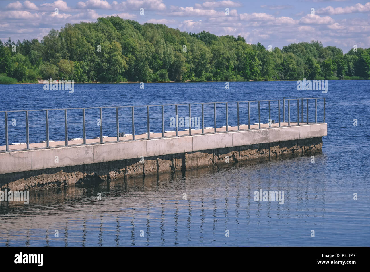 wooden and composite material foot bridge over water in green summer ...