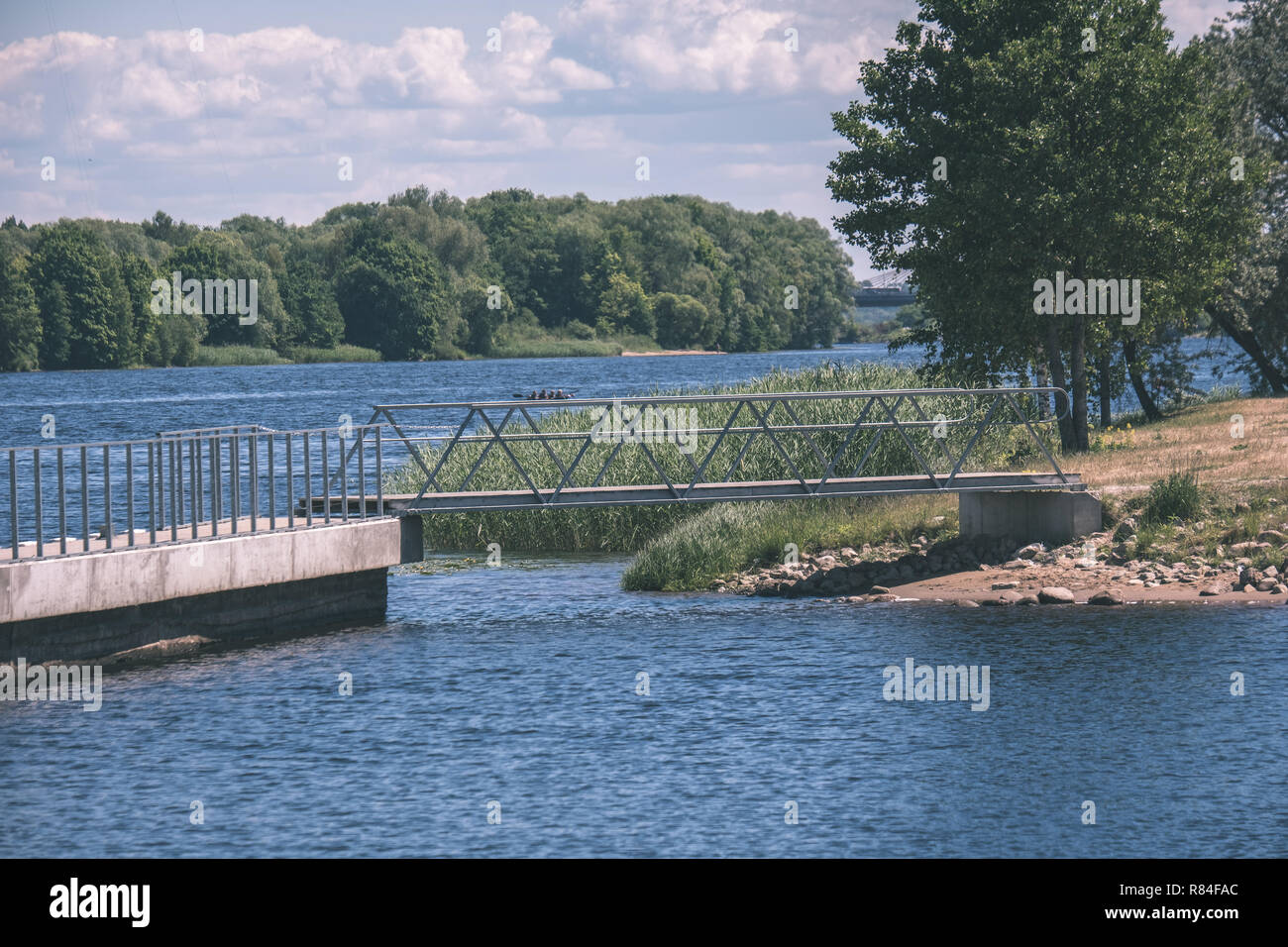wooden and composite material foot bridge over water in green summer ...