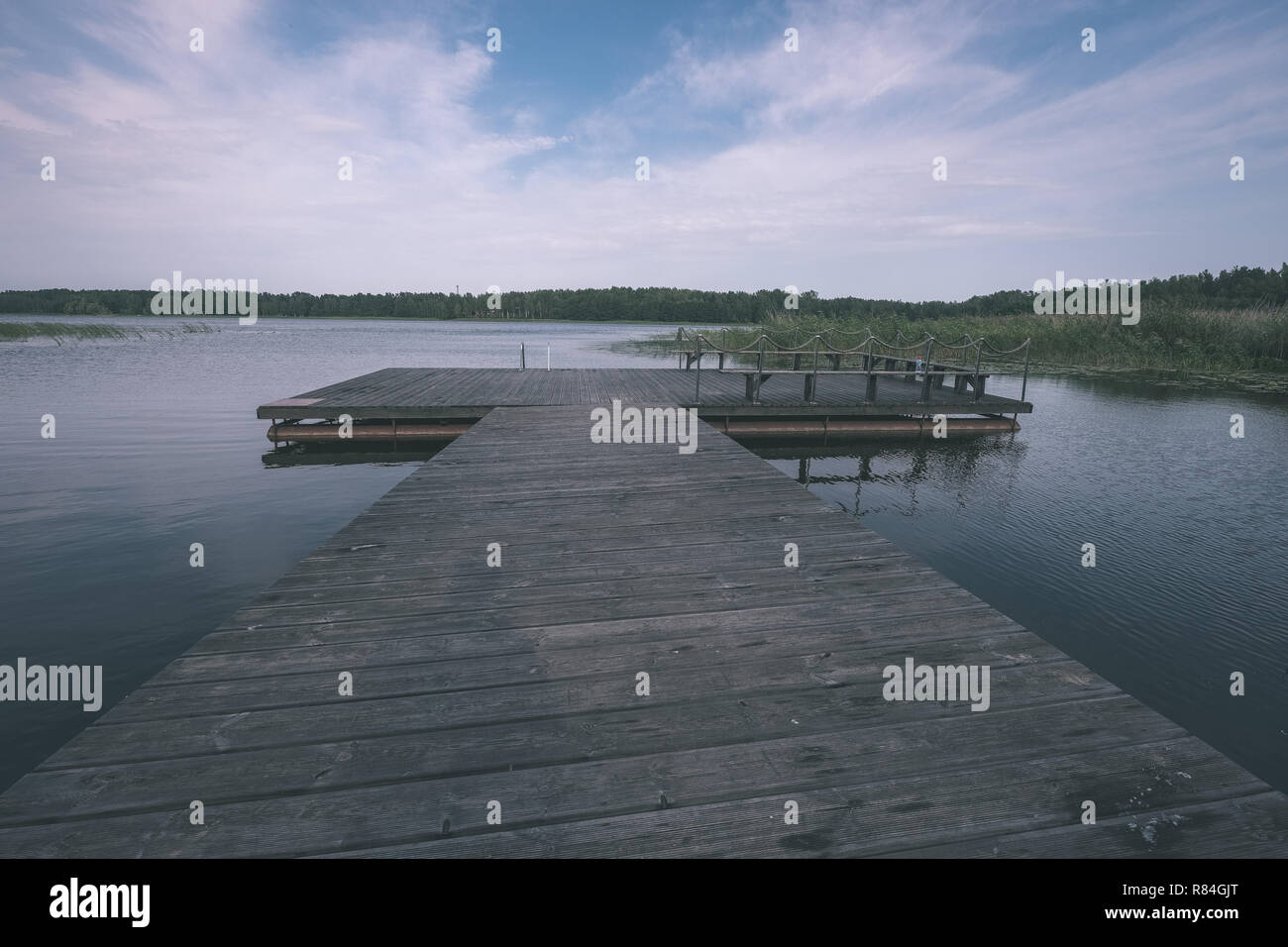 wooden and composite material foot bridge over water in green summer ...