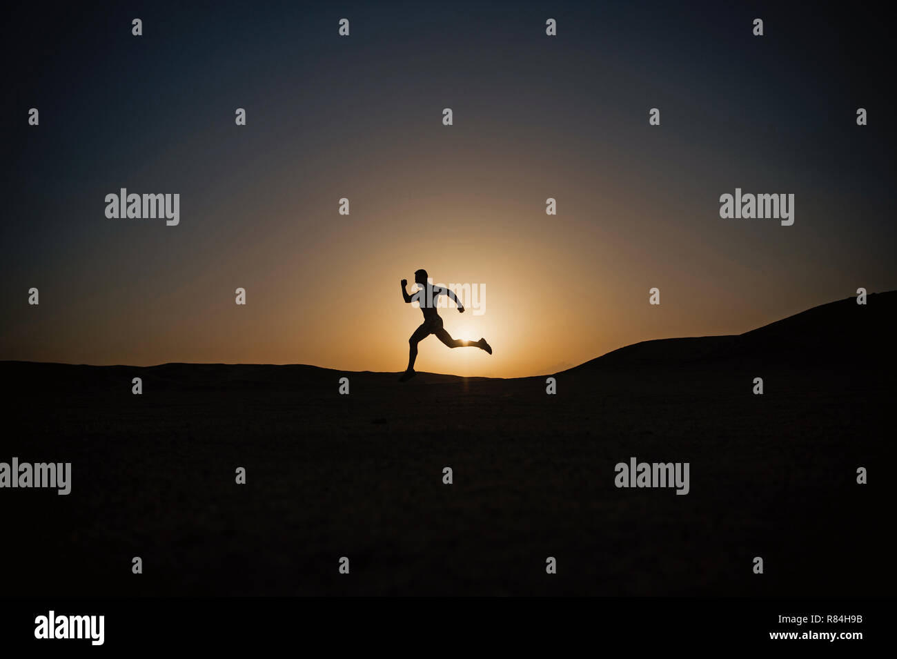 running man. silhouette of running man on sunset fiery sky background ...