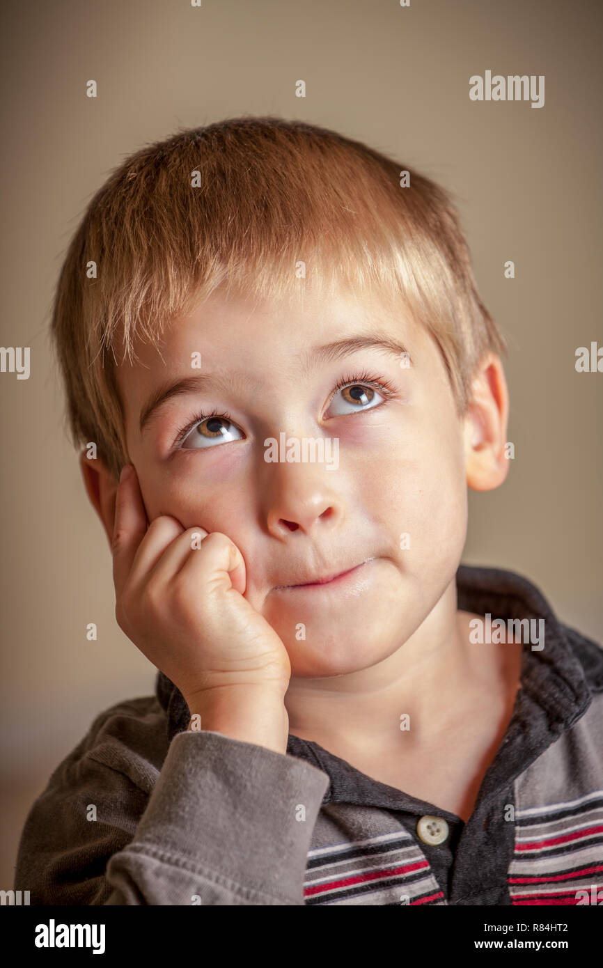 Cute four year old boy in a playful mood, showing that his is thinking ...