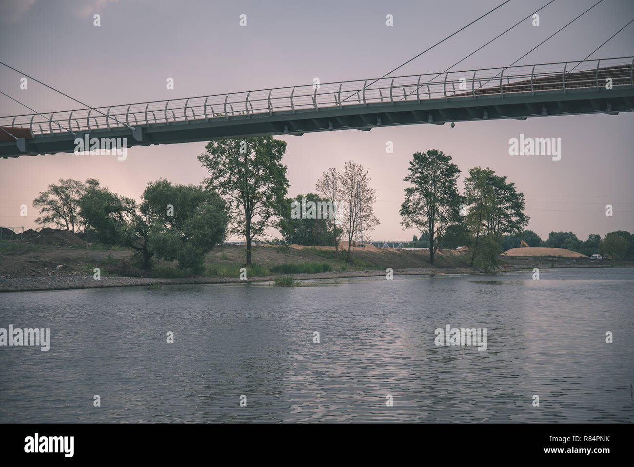 wooden and composite material foot bridge over water in green summer ...