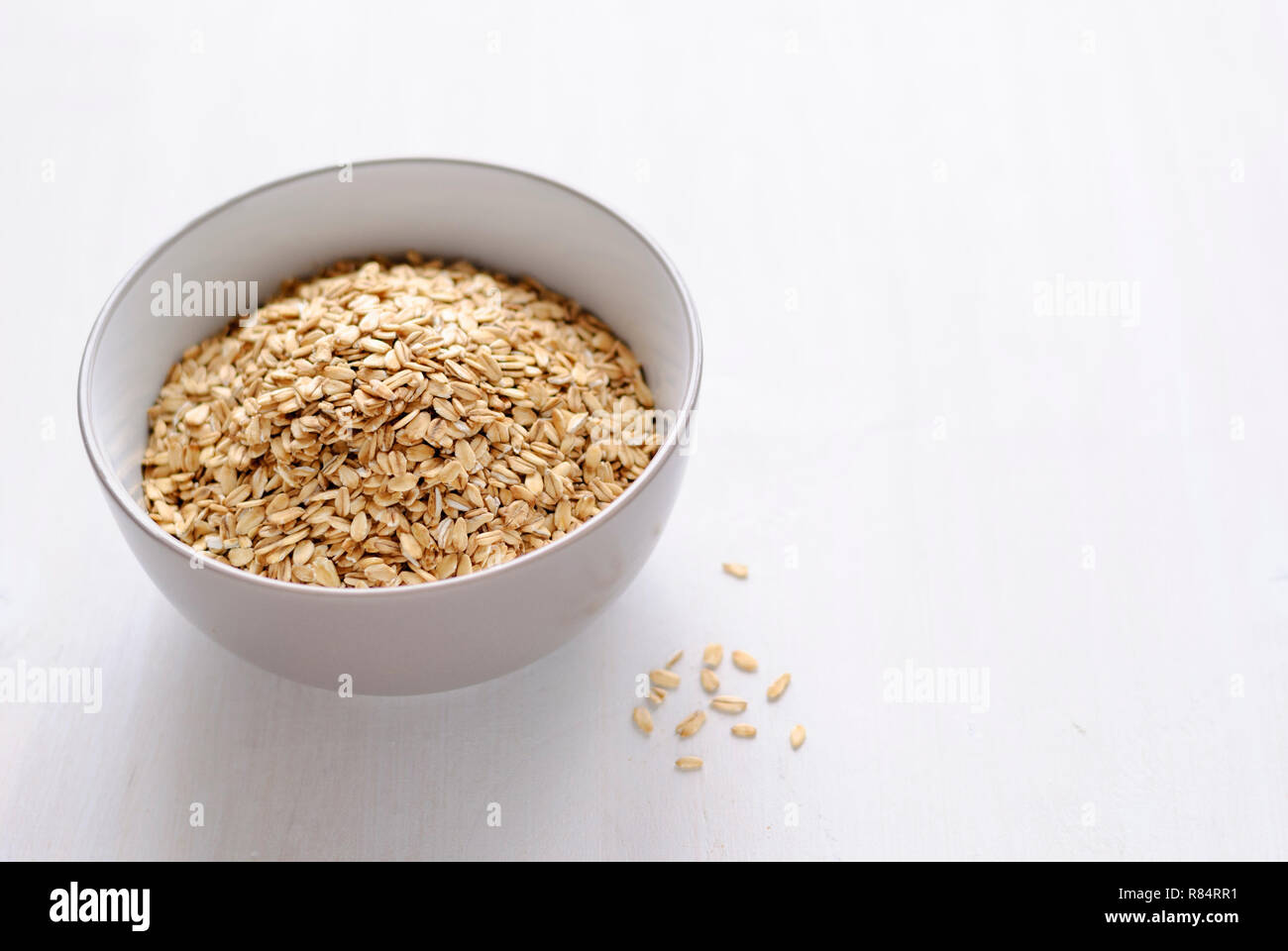 White ceramic bowl of dry oatmeal on white background with a shadow ...