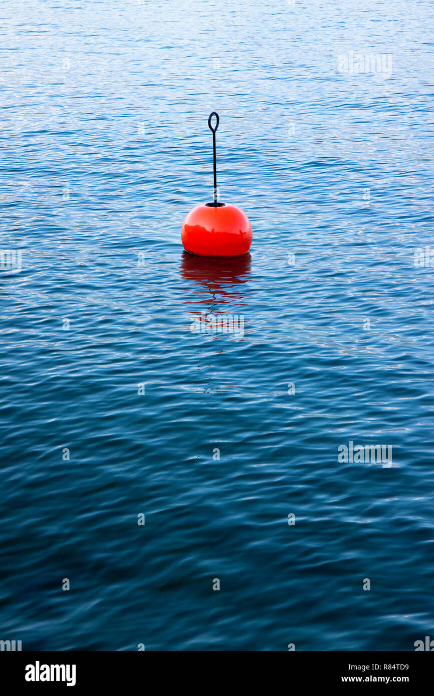 Red bouy on a calm lake isolated on blue background Stock Photo - Alamy