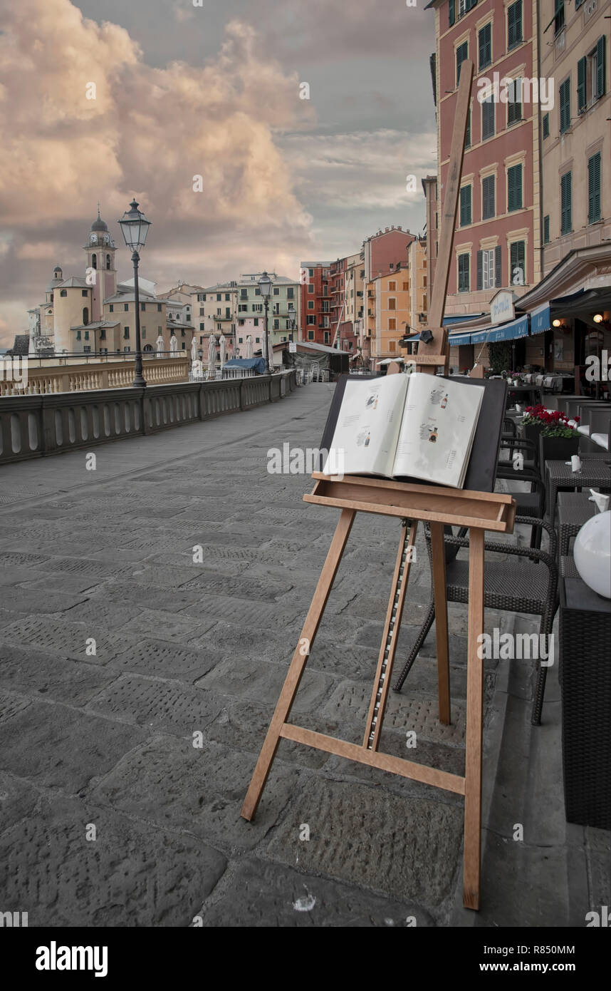 Open menu on street stand near outdoor tables of restaurant in Camogli ...