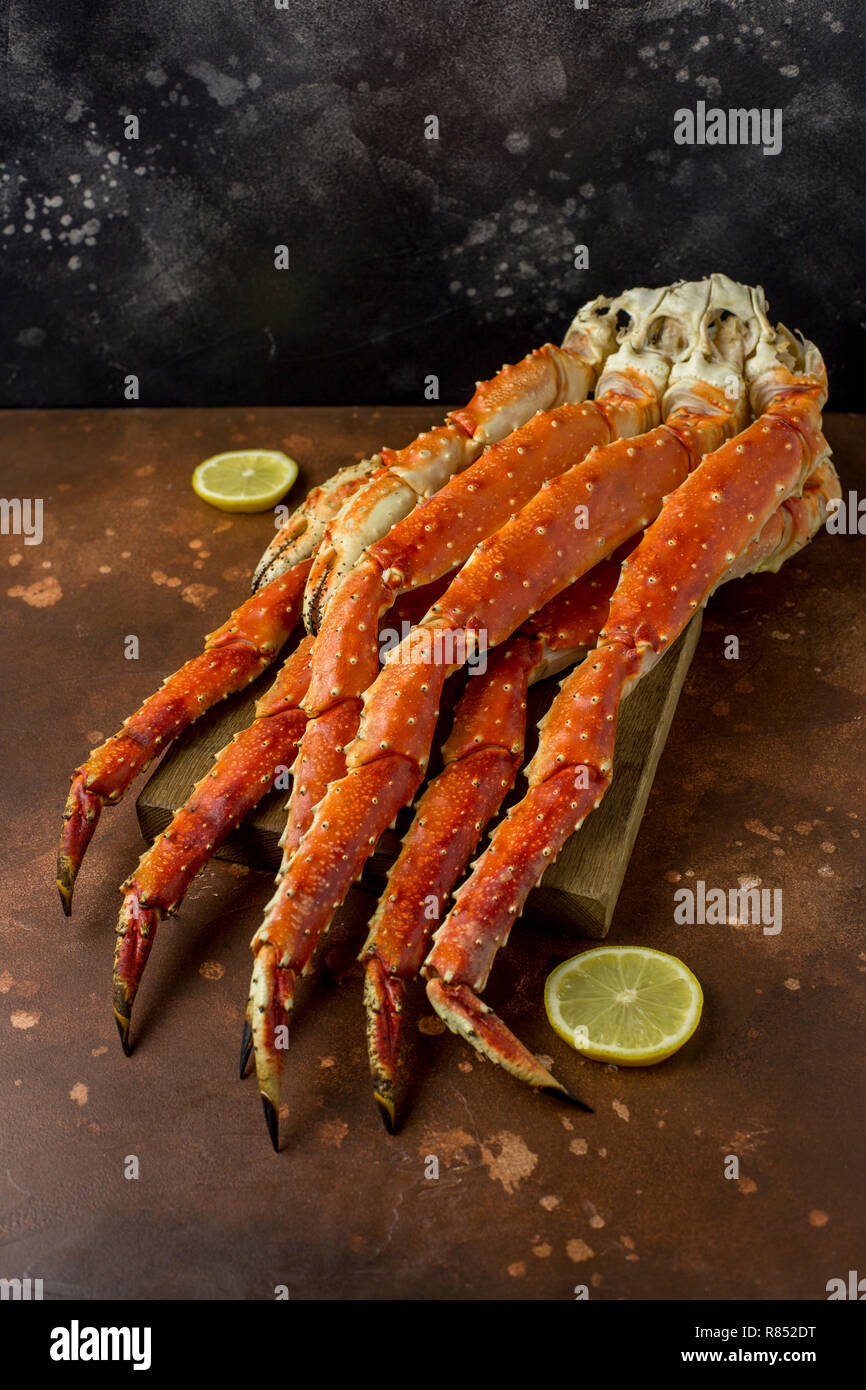 Fresh tasty king kamchatka crab's claw with lemon slices on wood board ...