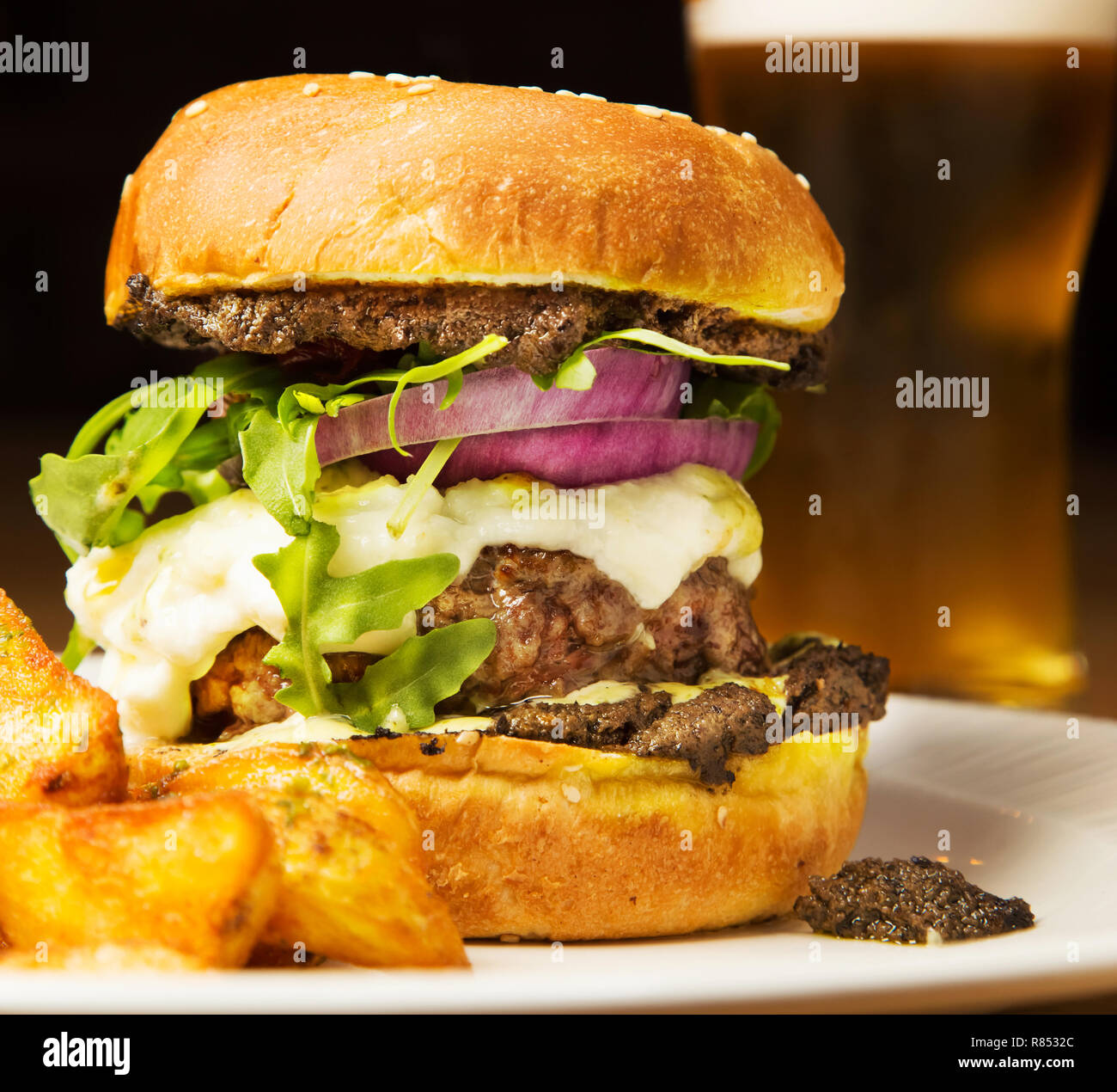 Classic burger in a bun with melting cheese and sauces on a table Stock ...