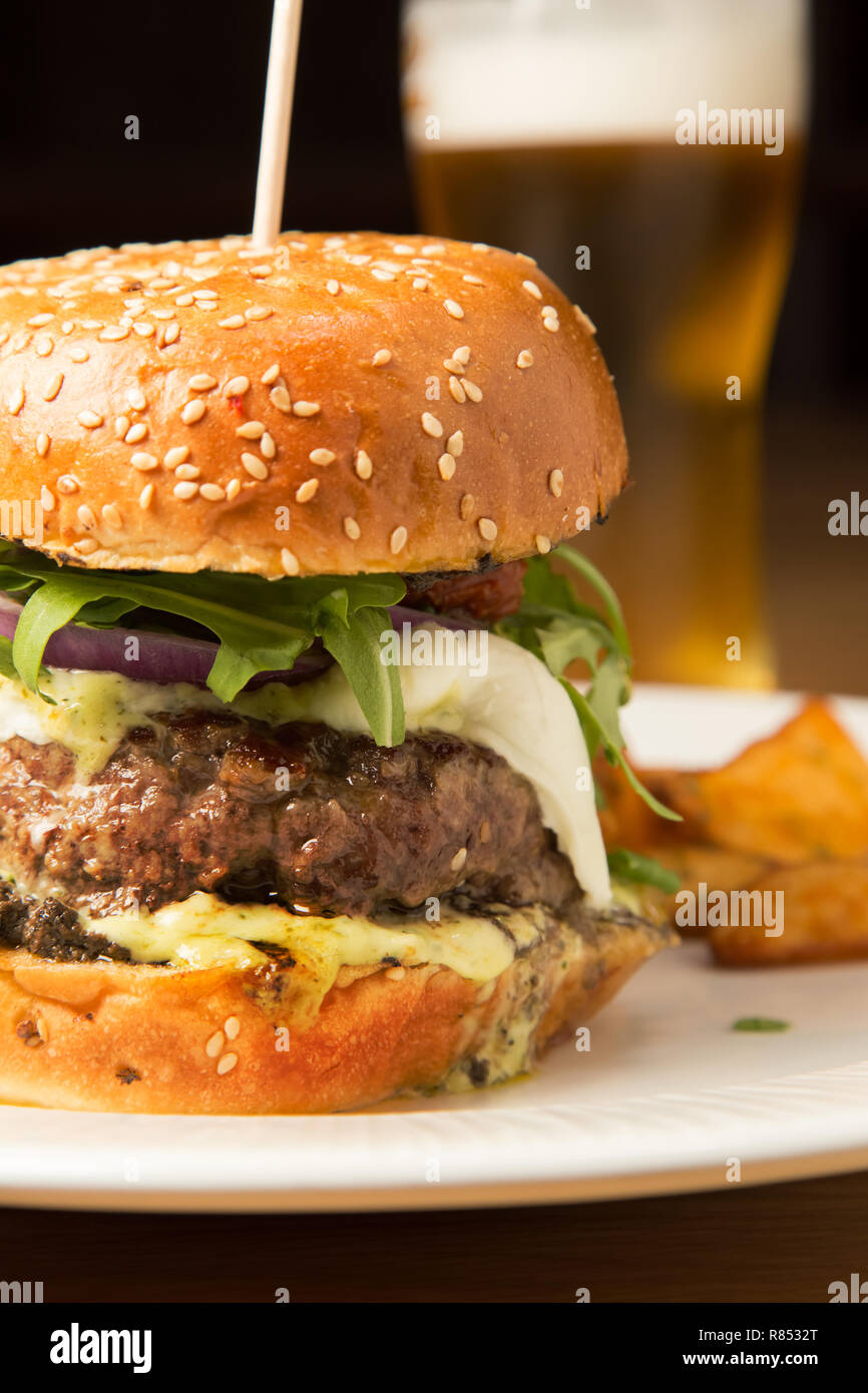 Classic burger in a bun with melting cheese and sauces on a table Stock ...