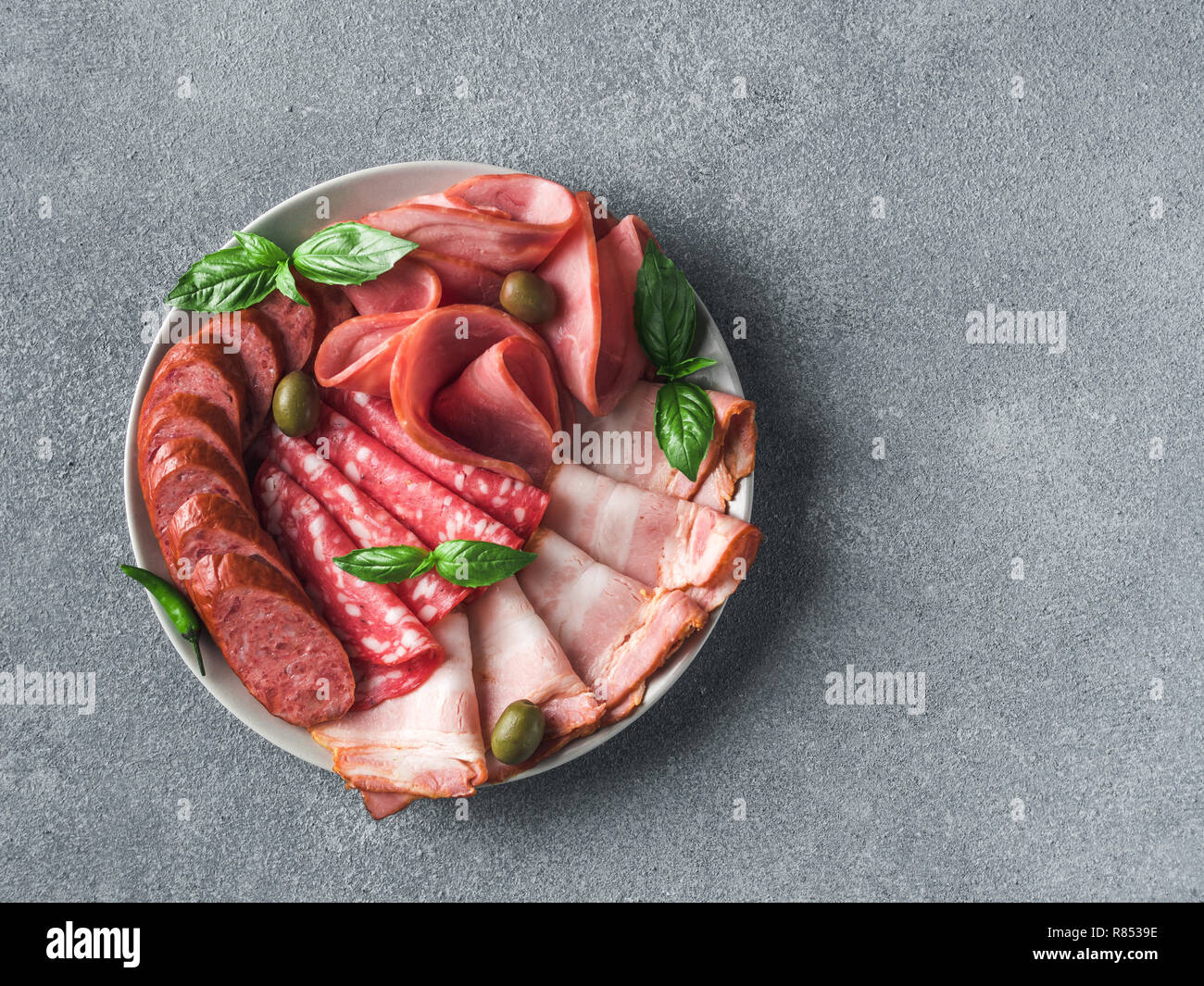 Antipasto set platter on plate over gray stone. Cold smoked meat plate ...