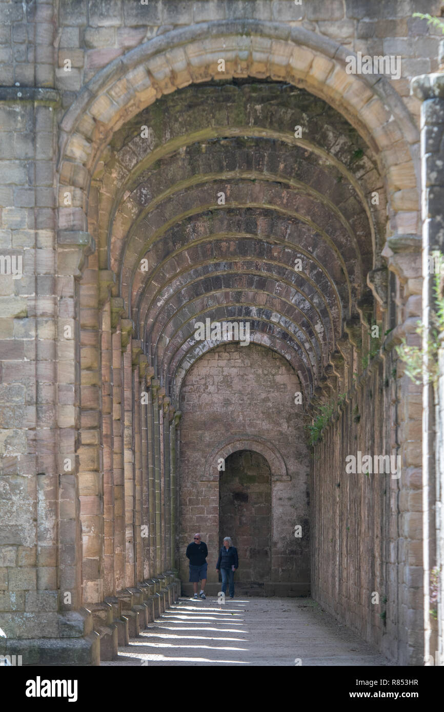 Rows and rows of arches repeat along a corridor in the Fountains Abbey ...