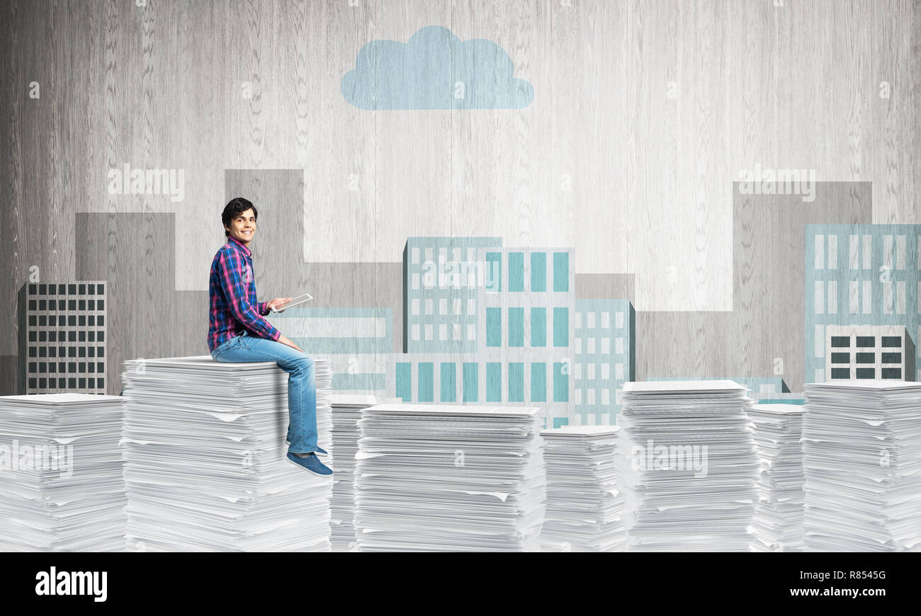Young man sitting on pile of paper documents Stock Photo - Alamy