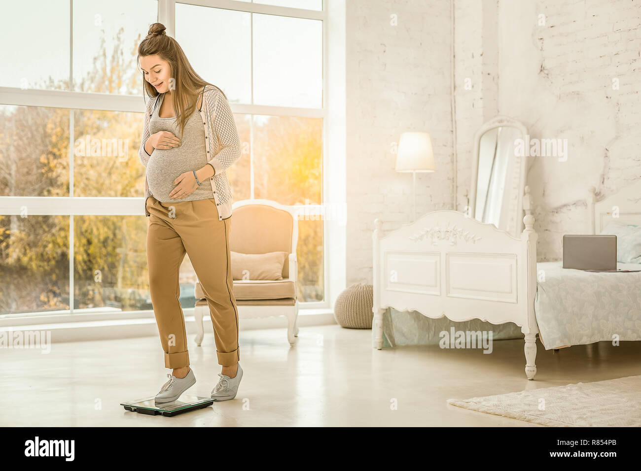 Checking the weight. The young woman tracking her weight at home while ...