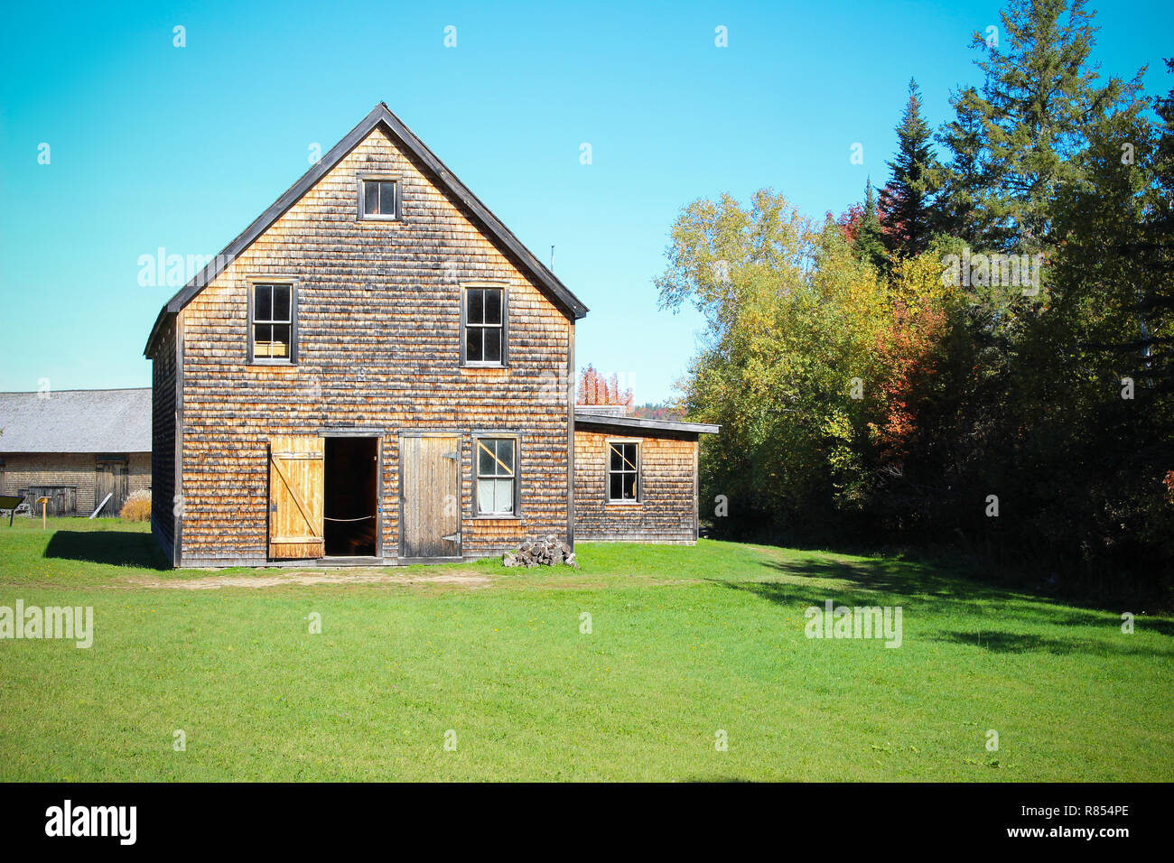 Quaint country wooden house surrounded by colorful autumn leaves with ...