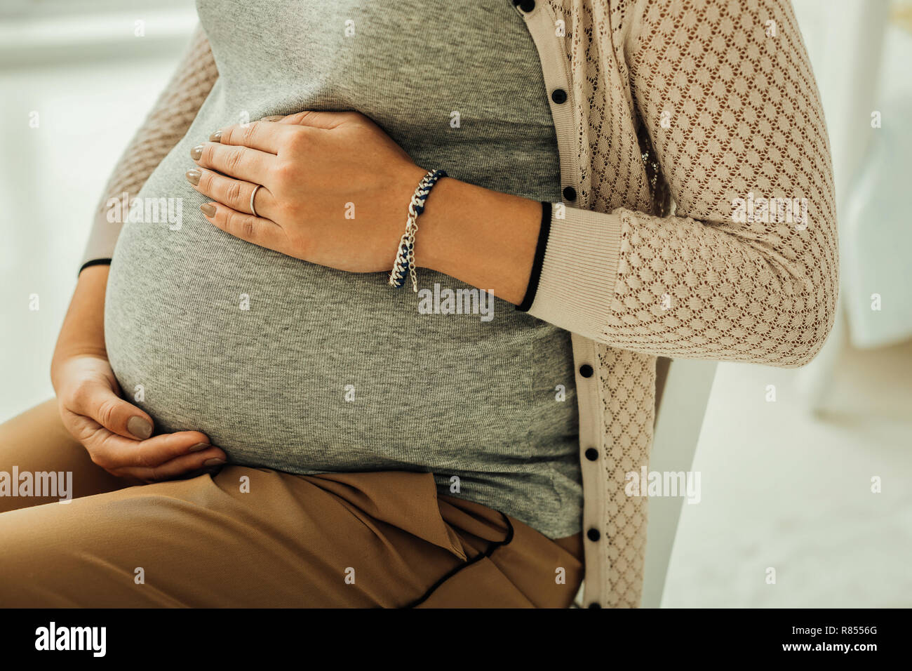 Pregnant belly. A woman touching her third-trimester pregnant belly ...