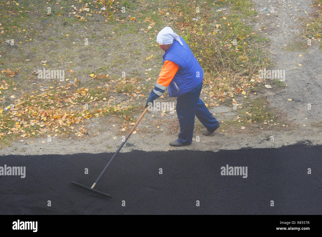 Female worker during asphalting road. Heavy female manual labor in ...