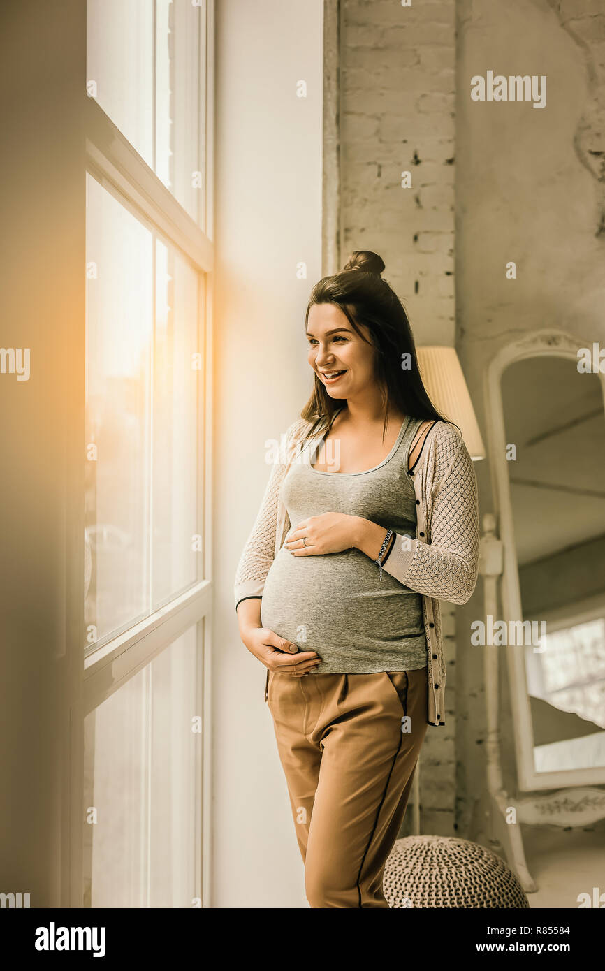 Expecting a baby. The beautiful young happily looking woman waiting for ...
