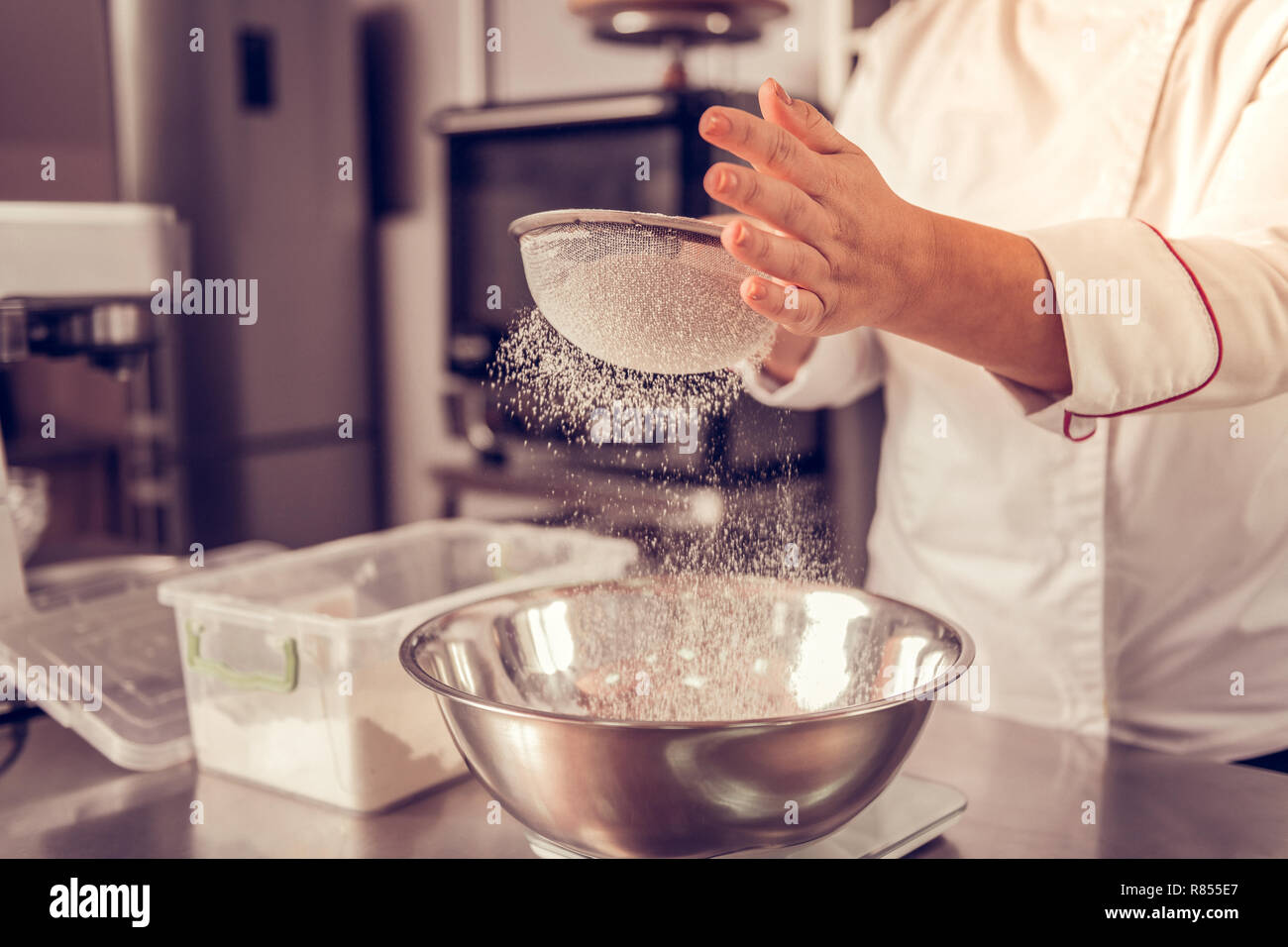 Kitchen equipment. Close up of a flout sifter being in female hands ...