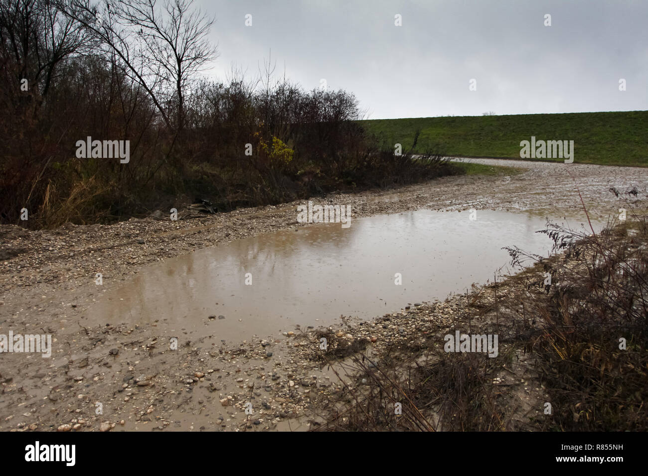 A muddy road with a large puddle in the countryside Stock Photo - Alamy