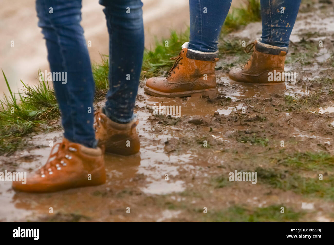 Two people standing in the mud with brown boots Stock Photo - Alamy