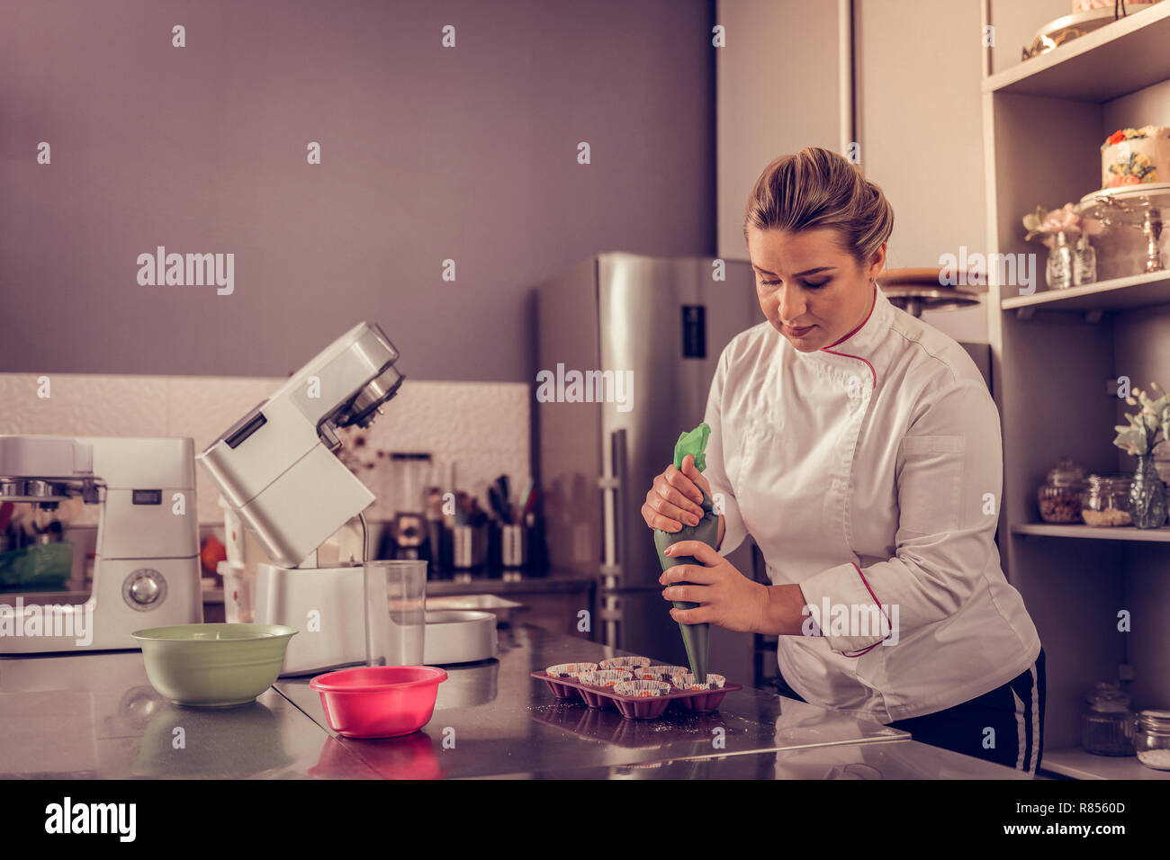 Famous chef. Pleasant young woman preparing muffins while participating ...