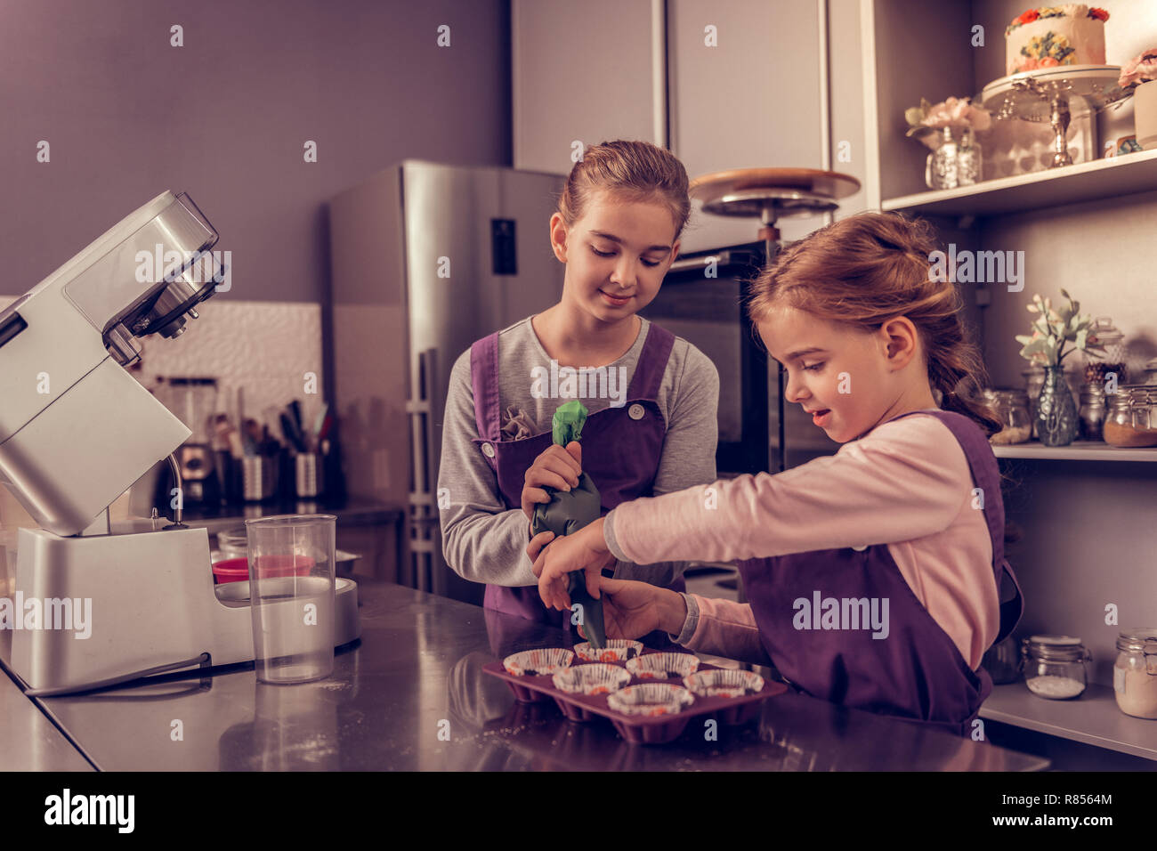 Two sisters. Positive nice girl being in the kitchen while cooking ...