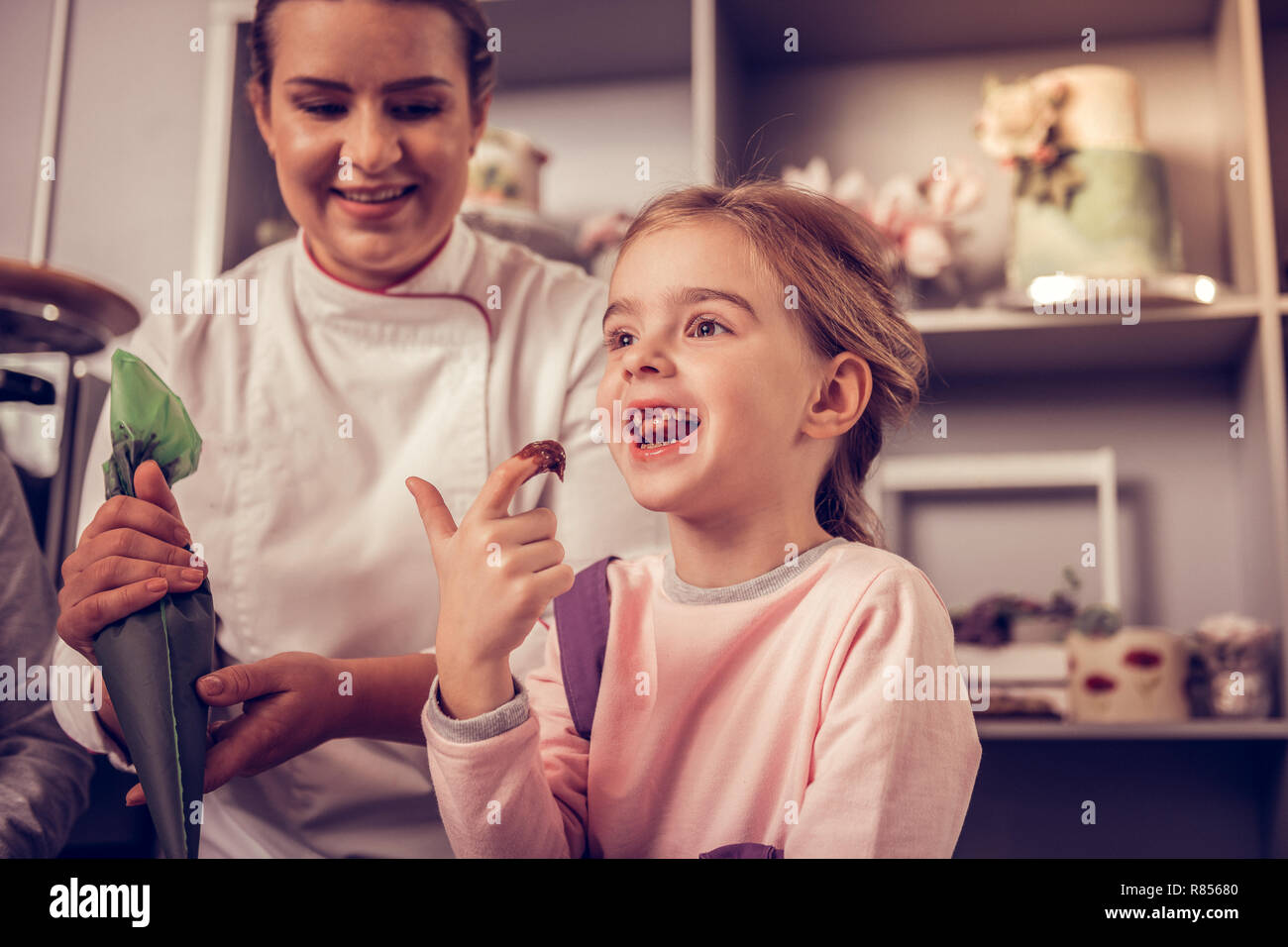 Best taste. Happy cute girl smiling while enjoying chocolate dough ...