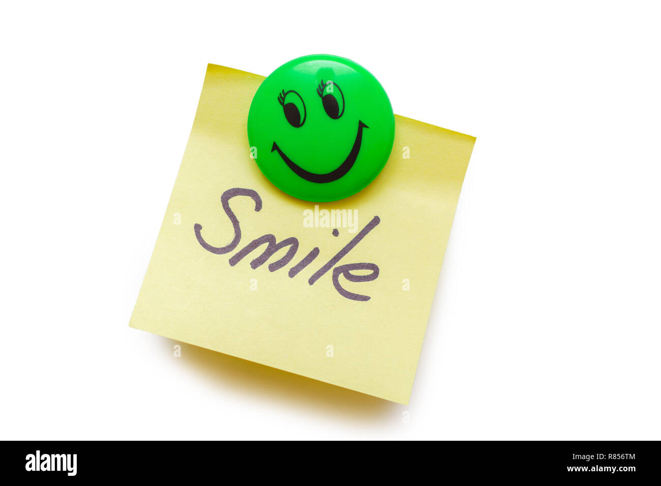Yellow paper for notes with the words smile on a magnet isolated on ...