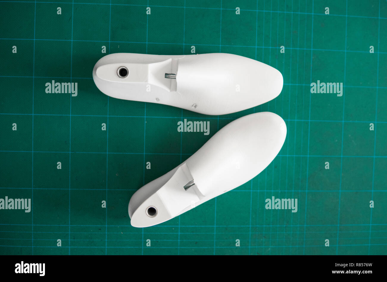 Two white plastic last shoe on rubber secondary cut cutting mat, The ...