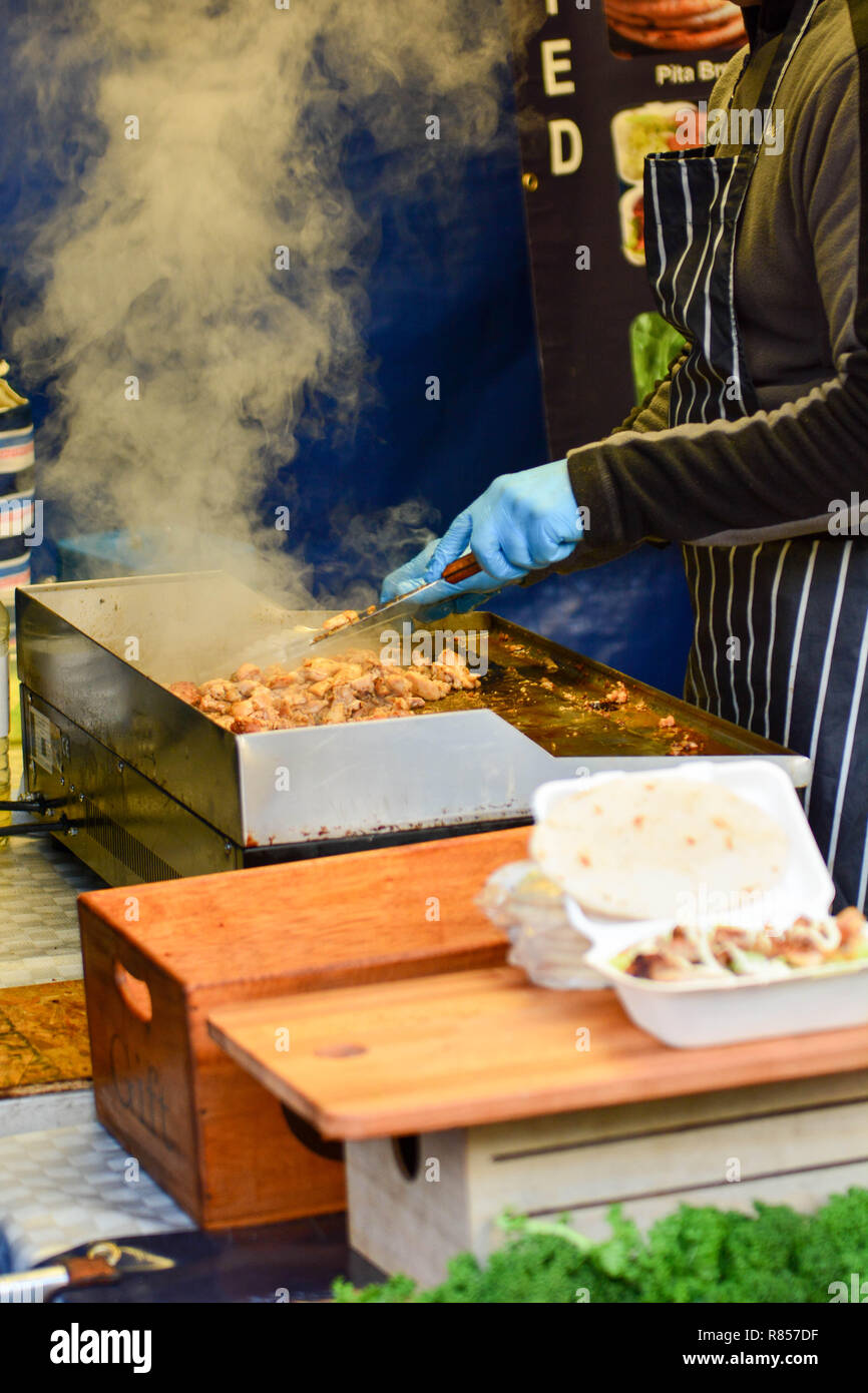 Street food vendor cooking pieces of chicken on portable hotplate at ...