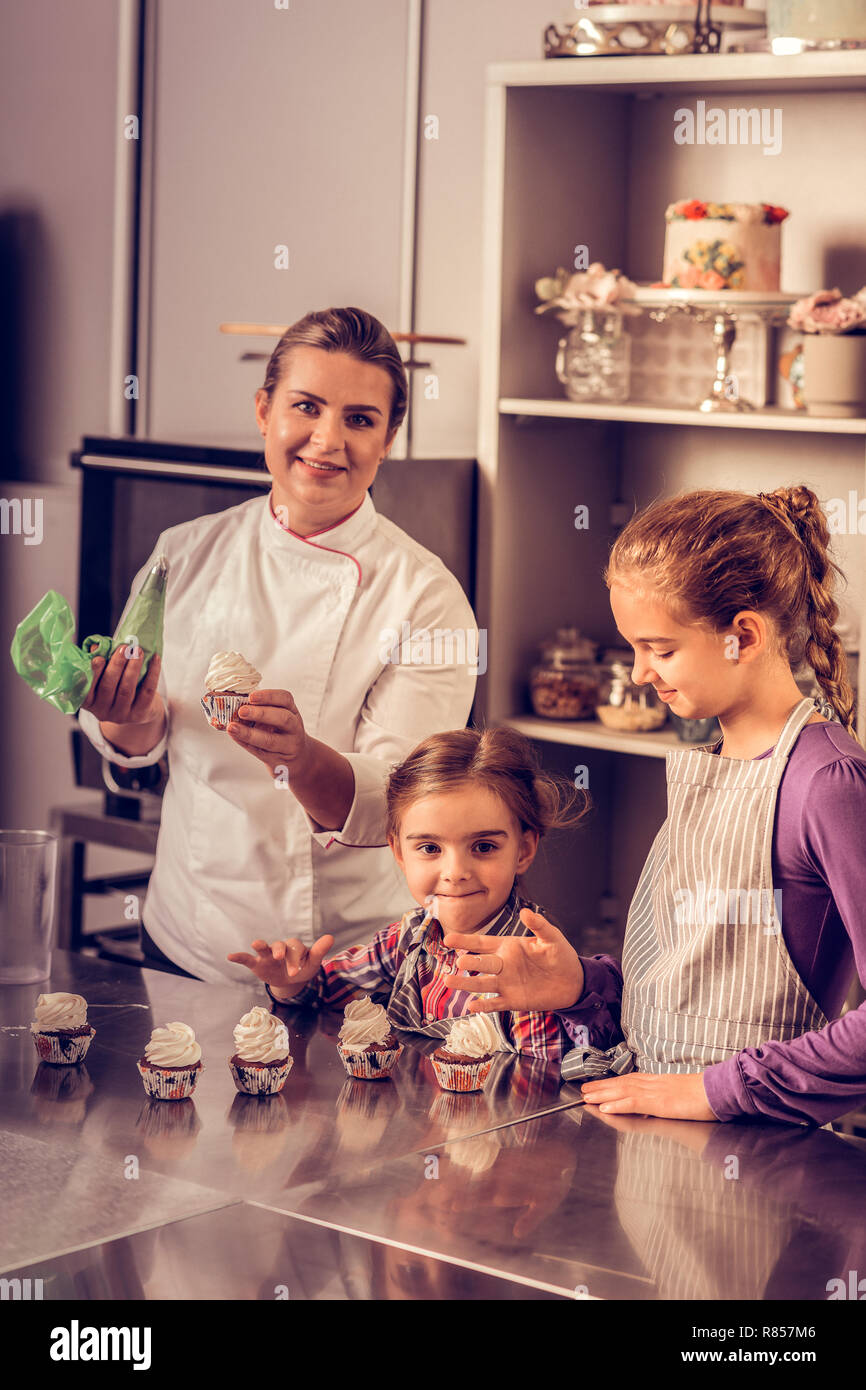 Preparation of sweets. Joyful nice girls learning how to prepare ...
