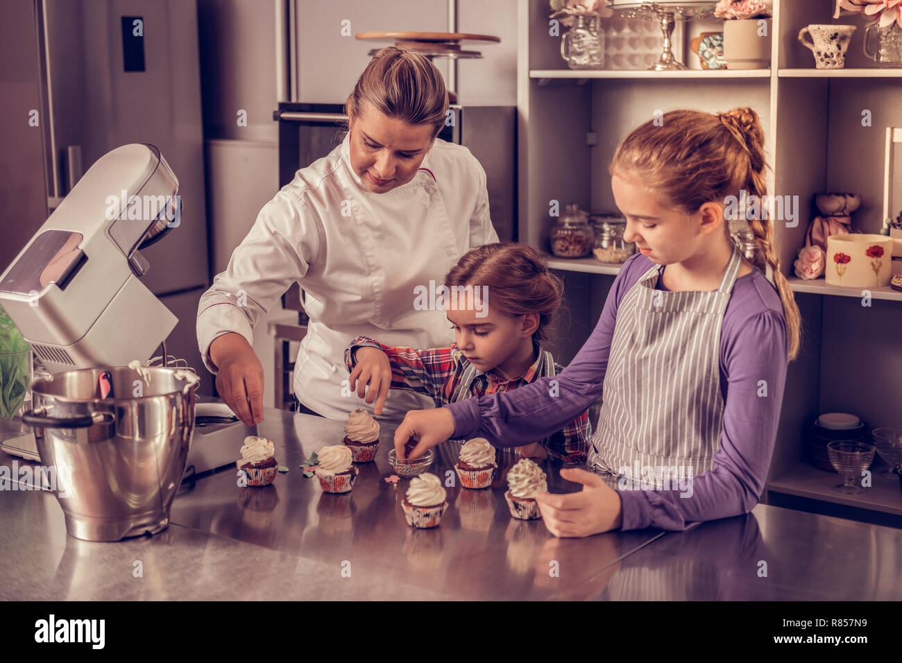 Cupcake master class. Positive pastry chef talking to her student while ...