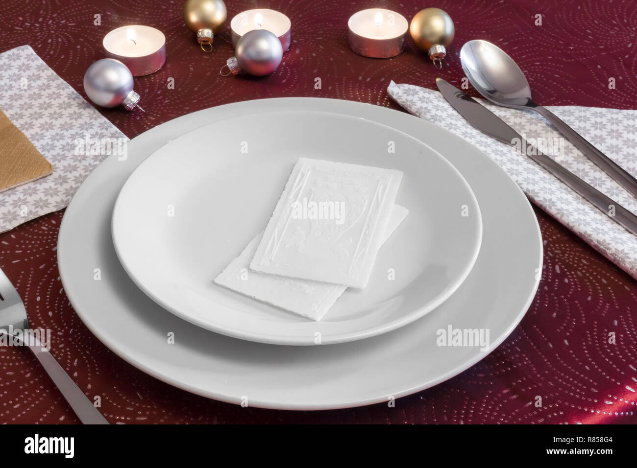 Christmas wafer on white plate on Christmas Eve table. Polish tradition ...