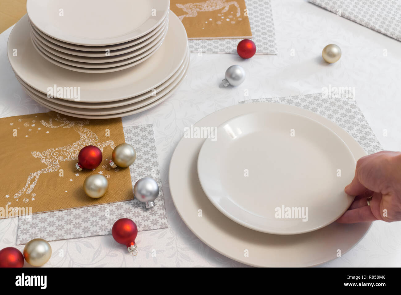 Hand is putting plate on holiday table. Preparing Christmas table Stock ...