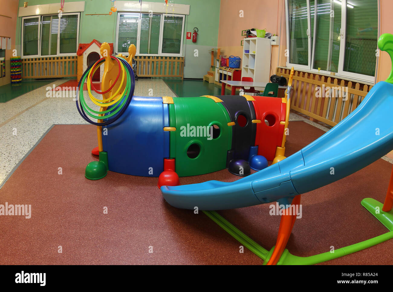 wide hall of a kindergarten with many toys and a plastic slide for ...