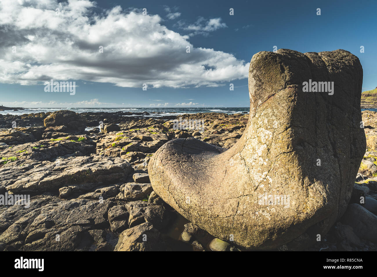 Close-up boulder on the stone beach. Cloudy rainy sky background. Northern Ireland shoreline ...