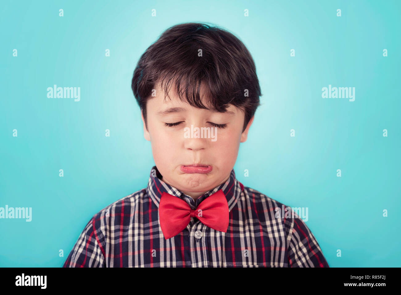 sad boy with bow tie on blue background Stock Photo - Alamy