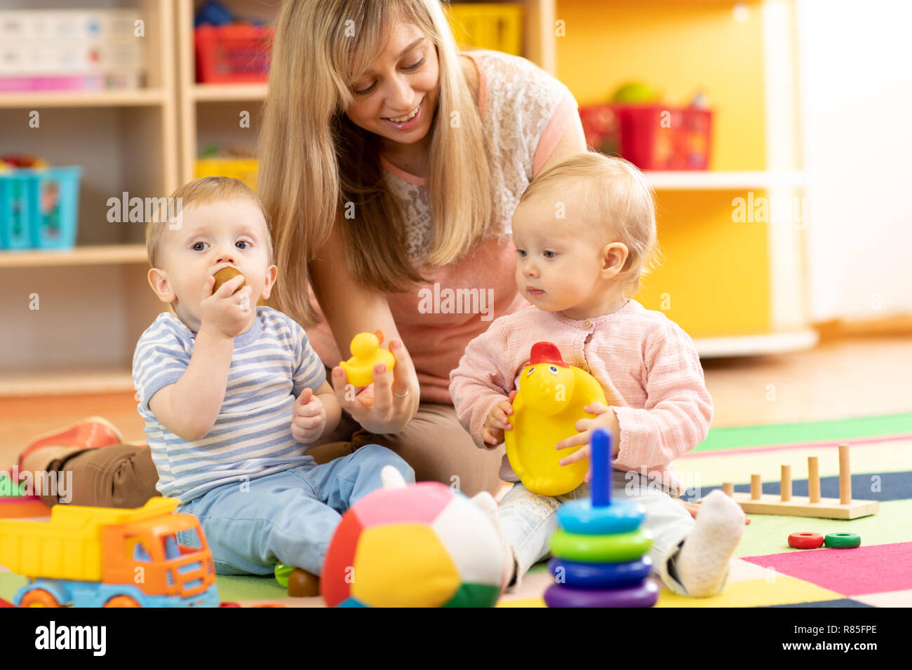 babysitter and children playing together in nursery or at home Stock ...