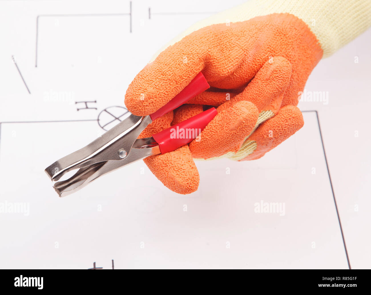 Hand hold electric clamps on a background of the electric scheme Stock ...