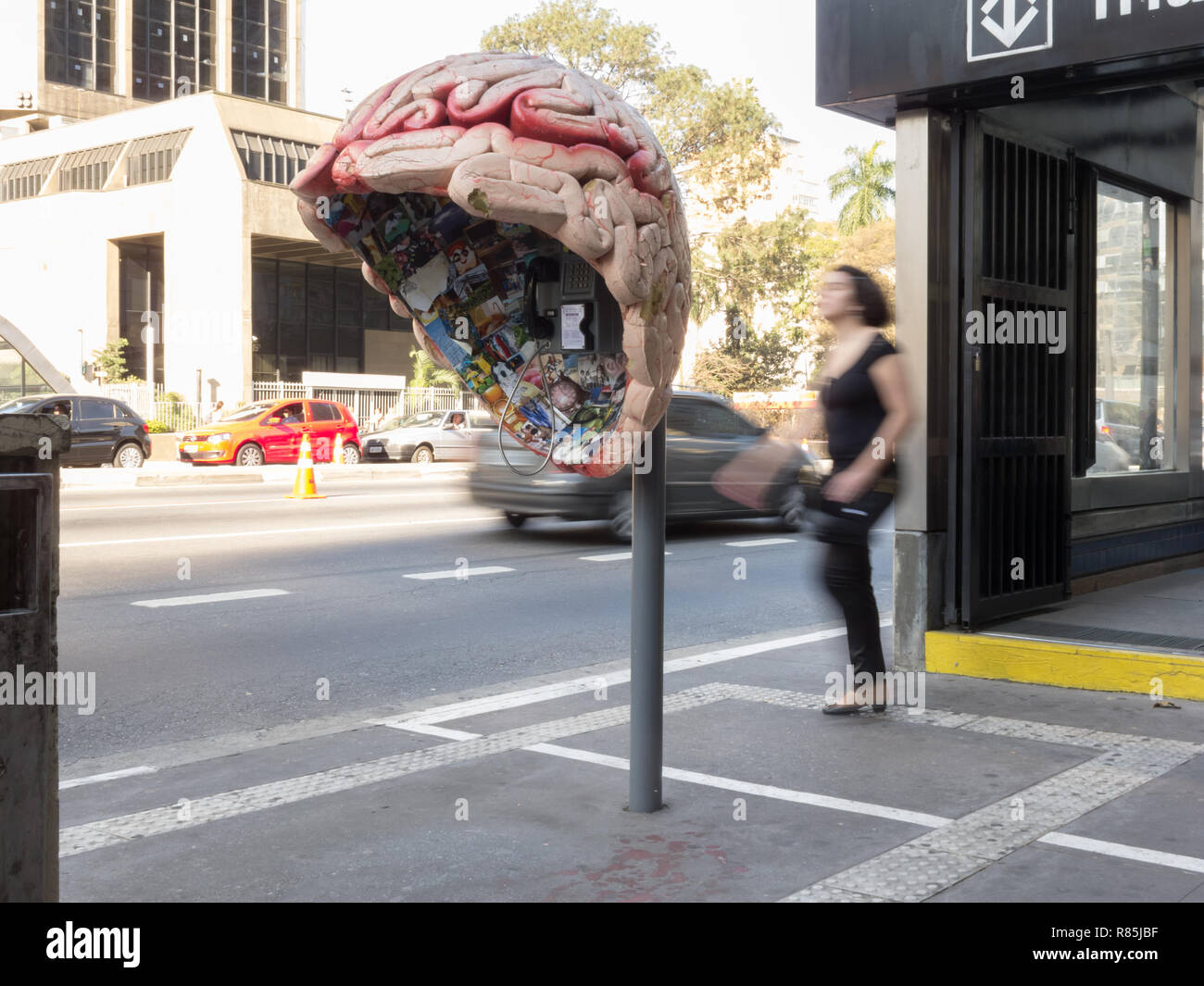 Passerby walks past behind giant brain-shaped phone booth street art ...