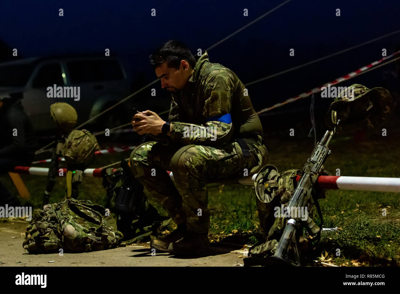 Side view serious soldier writing message in phone while wearing in ...